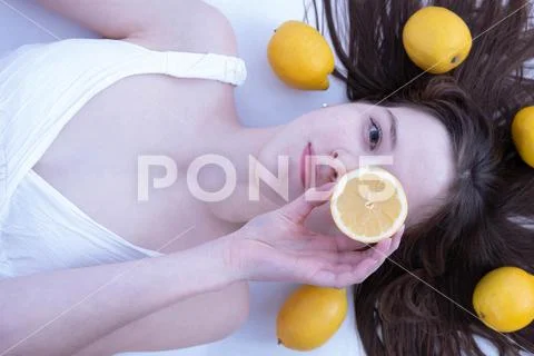 Young girl with half a lemon closes one eye Stock Photo #127744020