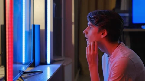 A young guy looks at the TV screen with ... | Stock Video | Pond5
