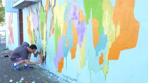 Young guy spraying graffiti on the build... | Stock Video | Pond5