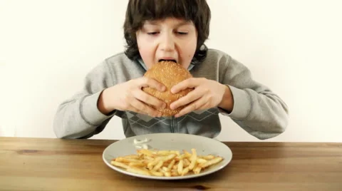 Young happy boy eating fast food, hambur... | Stock Video | Pond5