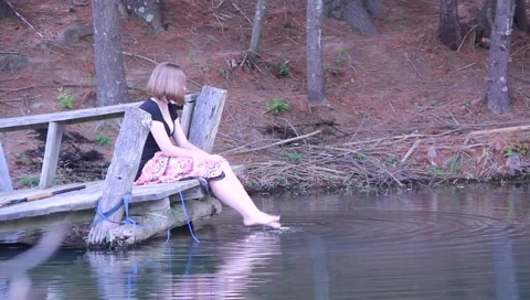 Young lady sitting on dock splashing fee... | Stock Video | Pond5
