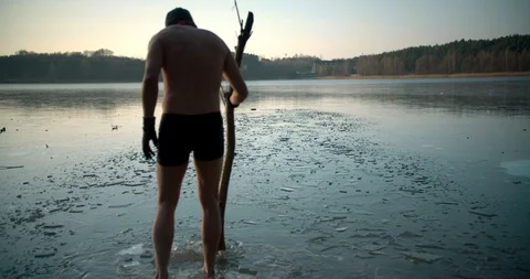 A young ma breaking ice on the river for... | Stock Video | Pond5