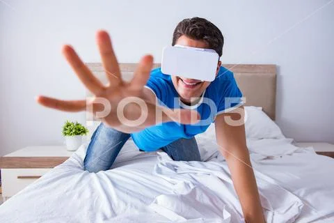 Young man in bed wearing a vr virtual reality head set Stock Photo ...