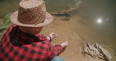 Young man dipping hands into lake. | Stock Video | Pond5