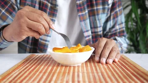 young man eating mango on table | Stock Video | Pond5