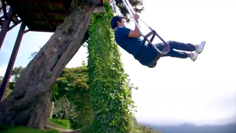 Young man goes high on rope swing by tre... | Stock Video | Pond5