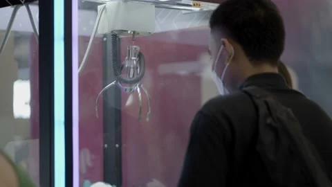 Young Man In Mask Playing Claw Machine A... | Stock Video | Pond5