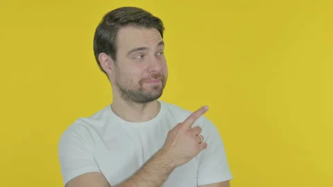 Young Man Pointing on Side on Yellow Bac... | Stock Video | Pond5