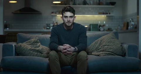 Young man sitting on the edge of a couch... | Stock Video | Pond5