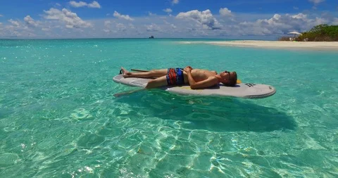 Young man sunbathing on surf board under... | Stock Video | Pond5