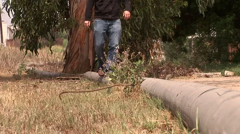 Young man walking along pipe in park | Stock Video | Pond5