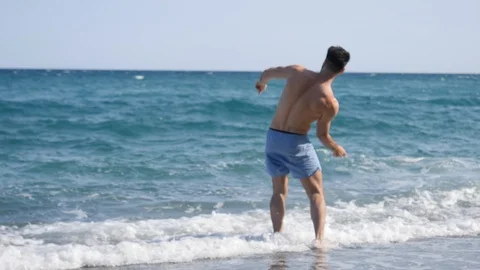 Young man walking around a beach alone | Stock Video | Pond5