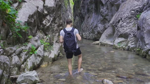 Young man walking in running water in ca... | Stock Video | Pond5