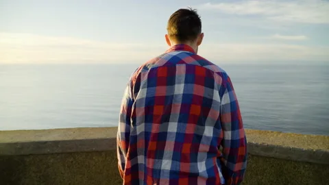 Young man walking towards the edge of a ... | Stock Video | Pond5