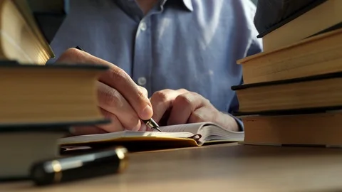 Young man writing in library. Piles book... | Stock Video | Pond5