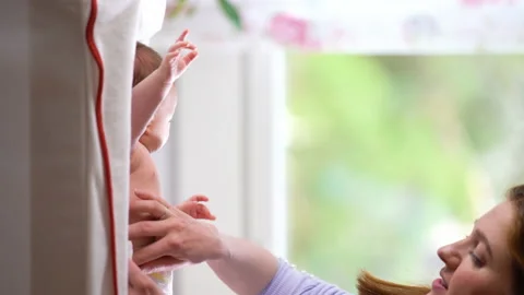 Young mother changing her baby's diaper | Stock Video | Pond5