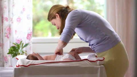 Young mother changing her baby's diaper | Stock Video | Pond5