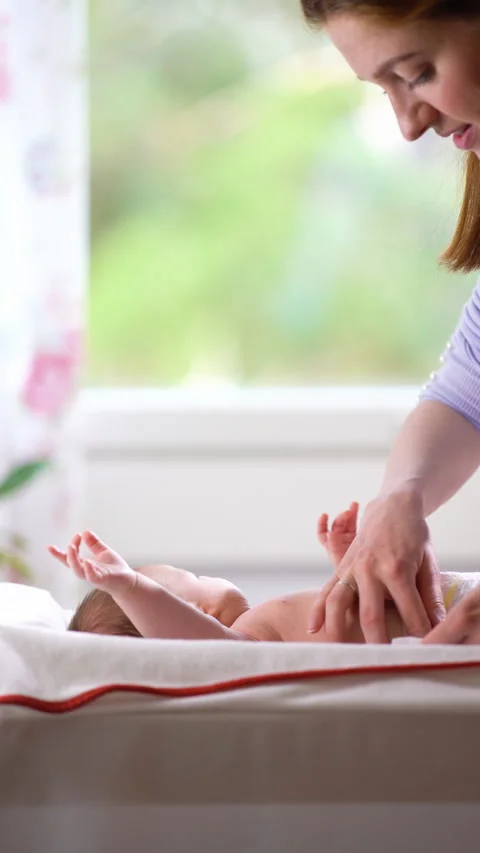 Young mother changing her baby's diaper | Stock Video | Pond5