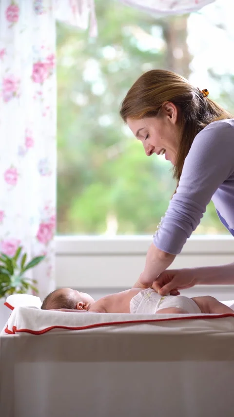 Young mother changing her baby's diaper | Stock Video | Pond5