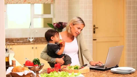 Young mother coping with baby and cookin... | Stock Video | Pond5