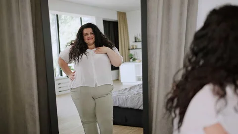 Young overweight woman looks at reflecti... | Stock Video | Pond5