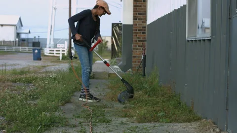 Young Person Weed Whacking Front Of Comm... | Stock Video | Pond5