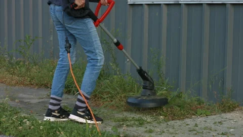 Young Person Weed Whacking Front Of Comm... | Stock Video | Pond5