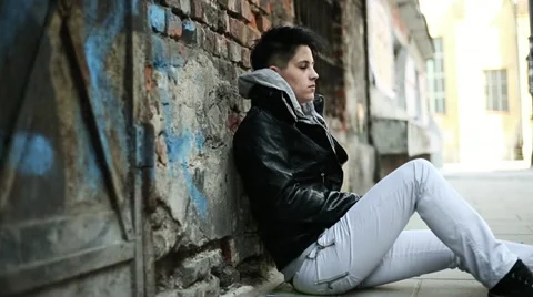 Young sad punk girl sitting by the wall ... | Stock Video | Pond5