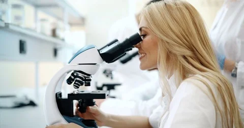 Young scientist looking through microsco... | Stock Video | Pond5