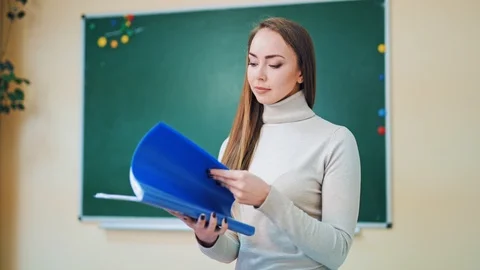 Young teacher with a folder in the class... | Stock Video | Pond5