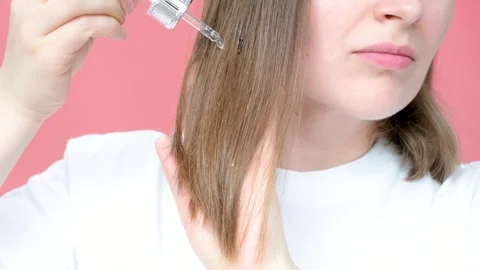 Young woman applying oil to her hair wit... | Stock Video | Pond5
