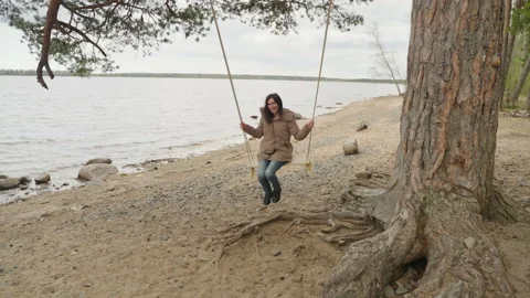 A young woman swings on a rope swing by ... | Stock Video | Pond5
