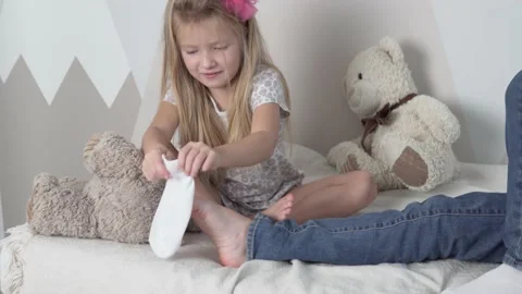 The younger sister cheerfully puts socks... | Stock Video | Pond5