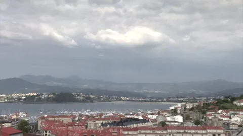 Zoom in to Cloudy sky from a coastal cit... | Stock Video | Pond5